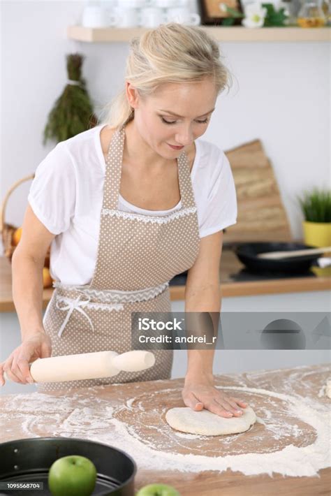 어린 소녀와 그녀의 금발 엄마 베이지색 앞치마 주방에서 반죽을 반죽 하는 동안 웃 고 재생에 대 한 수 제 과자 빵 피자 또는 쿠키를 구워 가족 재미와 요리 개념 2명에