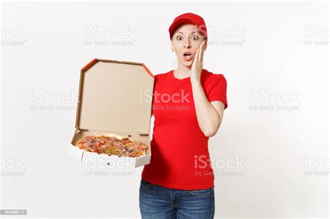 흰색 배경에 고립 된 빨간 유니폼에 배달 여자 꽤 여성 모자 티셔츠 청바지 택배 또는 골 판지 Flatbox에서 이탈리아 피자를 들고 딜러로 일하고 광고에 대 한 공간을