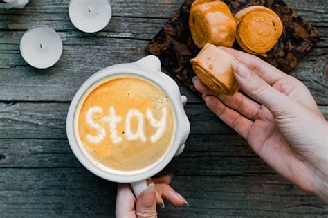 비문 패턴이있는 우유 거품이있는 검은 커피는 오래된 페인트와 나무 배경의 흰색 컵에 머물러 있습니다 면 봉과 양초로 둘러싸인