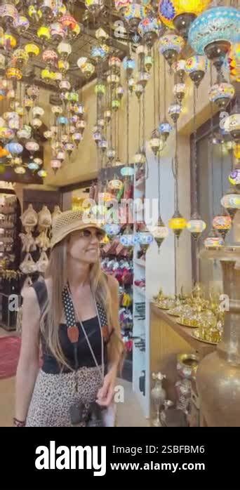 Blonde Woman Enjoys Her Time In A Bustling Market Surrounded By Dazzling Lanterns And Unique