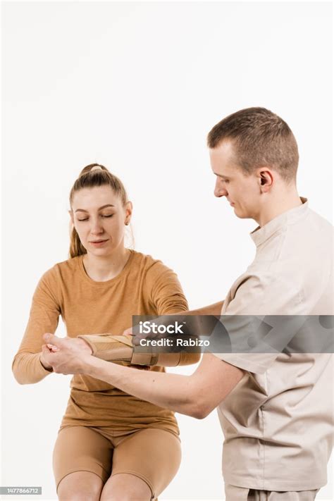 외상 전문의는 부상에서 회복하고 새로운 부상의 위험을 줄이기 위해 소녀의 손에 외부 손목 붕대를 감습니다 손목 관절의 병리학 적 이동성을 줄이기위한 손목 외부 보조기 25