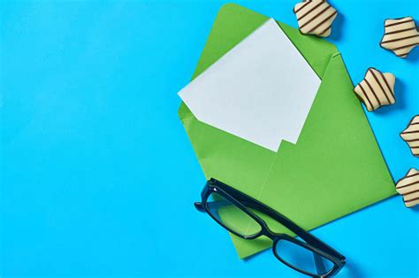 빈 종이 시트와 광학 안경녹색 봉투 근처에 흩어져있는 줄무늬 사탕은 파란색 책상에 놓여 있습니다 러브 레터 컨셉 텍스트의 공백입니다 맨 위 보기 0명에 대한 스톡 사진 및