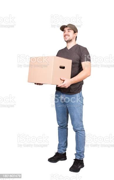 모자를 쓰고 전체 길이의 초상화를 입고 흰색 배경에 고립된 골판지 소포 상자를 들고 있는 쾌활한 배달 남자 해피 택배 배달 패키지 우수한 고객 서비스 개념 격리에 대한 스톡