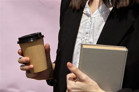 검은 색 뚜껑이있는 컵 갈색 종이를 들고 있는 손 커피 스페셜 오퍼 또는 프로모션 분홍색 배경에 컵을 들고 손을 차 나 커피 갈 수 있습니다 검은 뚜껑이 달린 갈색 종이 컵