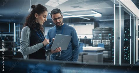 Portrait Of Two Female And Male Engineers Using Laptop Computer To Analyze And Discuss How To