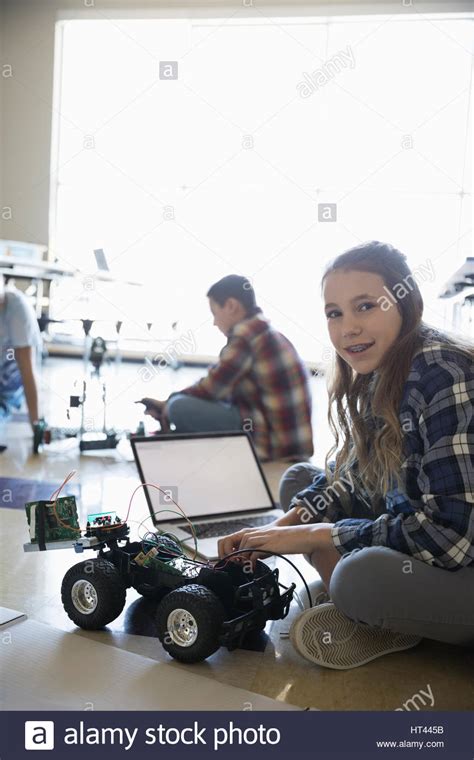 Portrait Confident Pre Adolescent Girl Programming Robotics At Laptop On Classroom Floor Stock