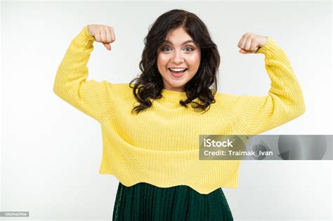 매력적인 갈색 머리 여자 에 A 노란색 스웨터 와 녹색 스커트 쇼 근육 올라 그녀의 손을 올라 에 A 흰색 배경 인물 사진에 대한 스톡 사진 및 기타 이미지 Istock