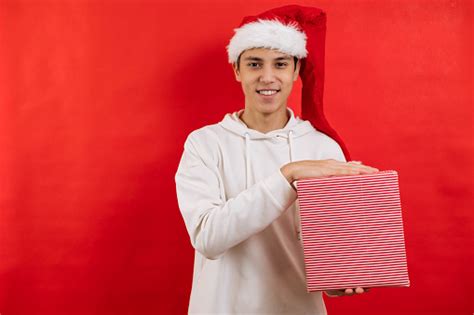 빨간 배경에 손에 선물을 들고 산타 모자를 쓴 청년의 초상화 복사 공간 십대 소년에 대한 스톡 사진 및 기타 이미지 십대