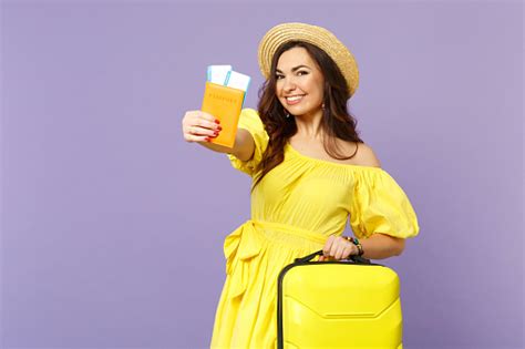 노란 드레스 여름 모자 개최 여행 가방 여권 탑승권 티켓 파스텔 바이올렛 벽 배경에 고립에서 아름 다운 젊은 여자 사람들은