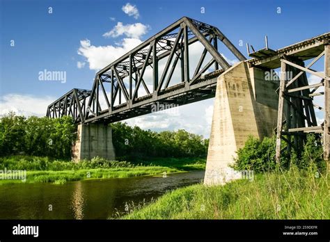 A Bridge Spans A River With A Green Grassy Bank On Either Side The