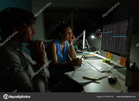 two diverse male female colleagues sitting desk using computer coding