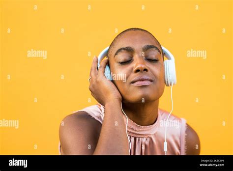 Dark Skinned Woman Listening To Music On Headphones With Eyes Closed