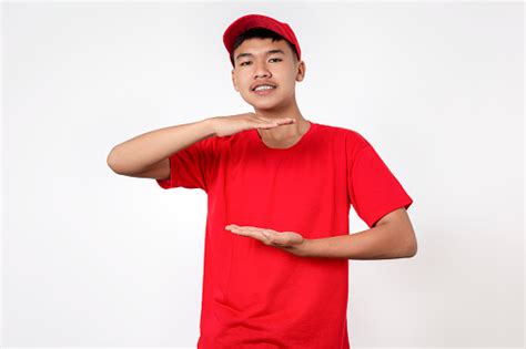 택배 배달 노동자 배송 개념입니다 흰색 배경에 고립된 빨간 유니폼을 입은 젊은 아시아 배달원이 크기 그림을 보여주는 손으로 몸짓을 하고 있다 18 19세에 대한 스톡 사진
