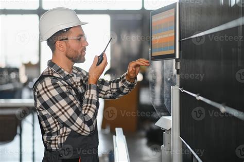 factory male bearded worker is programming a cnc milling machine with