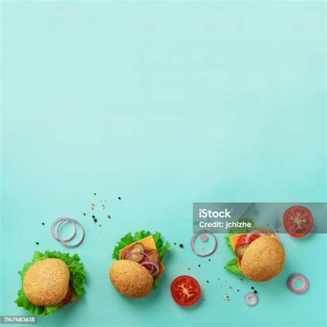 쇠고기 토마토 치즈 양파 오이 및 양상추 파란색 배경에 맛 있는 햄버거 정사각형 자르기 평면도 복사 공간 패스트 푸드 배너입니다 식사를 멀리 가져가 세요 건강에 해로운