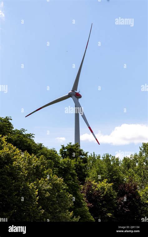 A Vertical Portrait Of A Windmill Standing High Above The Trees In A