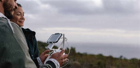 Young Couple Navigating A Flying Drone With Remote Control Man And