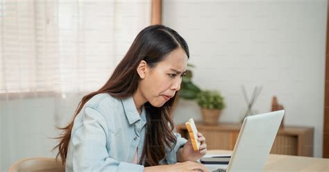 아시아 매력적인 사업가는 노트북 컴퓨터에서 사업을 실행하는 동안 서둘러 입 가득 빵을 먹고 배고프다 아름답고 진지한 학생은 좌절감을 느끼고 집에서 일하고 공부하느라 바쁘다