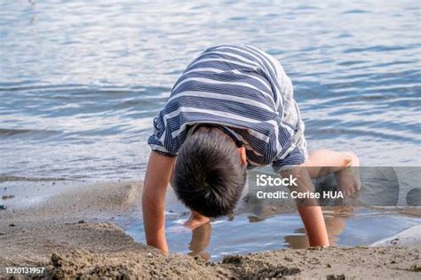 모래를 연주하는 아이는 해변에서 머리를 합니다 스위스의 물 옆에서 캐주얼한 옷을 입은 한 어린 아시아 소년 건강한 생활방식에 대한 스톡 사진 및 기타 이미지 Istock