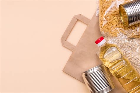 음식물 공급이 있는 종이 봉투는 밝은 노란색 배경에 식량 공급을 위기 복사 공간 진주 보리 파스타 통조림 식품 해바라기 기름 음식 배달 기부 코로나바이러스 기부함에 대한