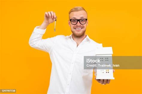 숙소 주인은 복사 공간이있는 노란색 배경에 집 모델과 열쇠를 손에 들고 있습니다 20 24세에 대한 스톡 사진 및 기타 이미지 20 24세 가능성 가정 생활 Istock