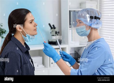 Laboratory Testing Doctor In Uniform Taking Sample From Patients Nose With Cotton Swab At