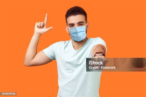 당신은 패자입니다 패자 제스처를 보여주는 흰색 티셔츠에 의료 마스크와 보스 화가 남자의 초상화와 카메라를 가리키는 당신의 패배를 조롱 20 29세에 대한 스톡 사진 및 기타