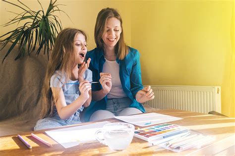 어머니와 딸이 그림을 그립니다 미술 교사는 수채화 물감 구 아슈를 적용하는 기술을 가르치고 브러시를 올바르게 잡는 방법을 가르칩니다 행복한 어린 시절 개념입니다 웃는 사람들