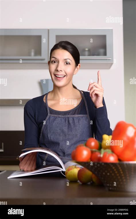 Happy Middle Aged Woman Wearing Apron Standng At The Kitchen Counter
