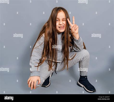 Girl With Long Hair Squats And Shows Victory Sign With Her Fingers