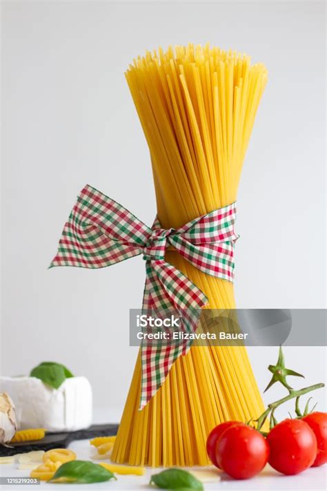 흰색 배경에 국기의 색상에 코드와 묶여 조리되지 않은 긴 이탈리아 스파게티의 무리 체리 토마토 바질 체스와 함께 제공됩니다 이탈리안 파스타 스파게티 생 0명에 대한 스톡