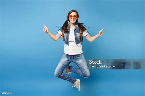 오렌지 하트 안경에 젊은 재미 여자 학생의 전체 길이 초상화 파란색 배경에 표시 엄지손가락 절연 교차 다리 점프 대학에서 교육입니다 광고에 대 한 공간을 복사 합니다 20