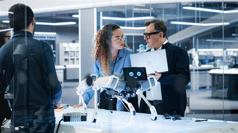 Tim Spesialis Robotika Industri Yang Beragam Berkumpul Di Sekitar Meja Dengan Robot Bergerak