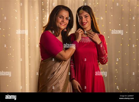 Mother With Adult Daughter In Traditional Dress Looking In Mirror Stock