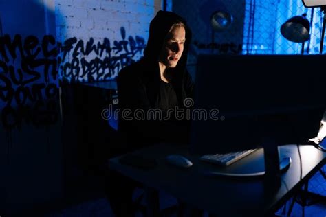 Medium Shot Portrait Of Hidden Hacker Man Wearing Sweatshirt With Hood Engaged In Hacking Into