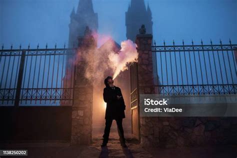 남자는 오래 된 건물에 대 한 전자 담배를 연기 안개와 증기와 신비한 사진 건강관리와 의술에 대한 스톡 사진 및 기타 이미지 건강관리와 의술 검은색 검정색 배경