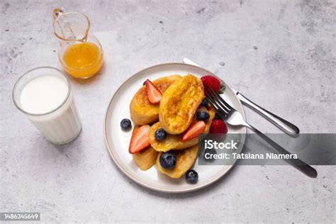 Torrijas 오렌지 토핑 유약 신선한 블루 베리 녹색 접시에 딸기 나무 테이블과 함께 제공되는 스페인 스타일의 프렌치 토스트 오렌지의 절반 스페인 디저트 평면 0명에