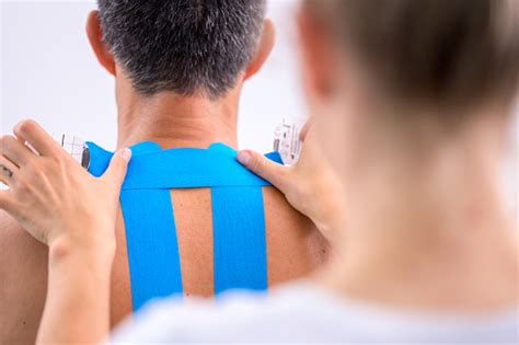 남자의 등에 파란색 키네시오 테이프를 적용 하는 여성 물리 치료사 근육 서포트 테이프에 대한 스톡 사진 및 기타 이미지 근육 서포트 테이프 25 29세 2명 Istock