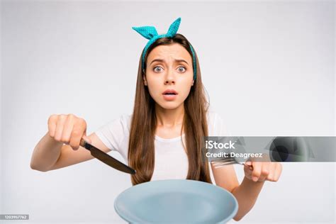 그녀의 클로즈업 초상화 그녀의 좋은 매력적인 우울한 배고픈 소녀 손 포크 나이프 그릇을 들고 원하는 식용 유용한 재료 빈 접시 밝은 흰색 색상 배경 위에 고립 T 셔츠에