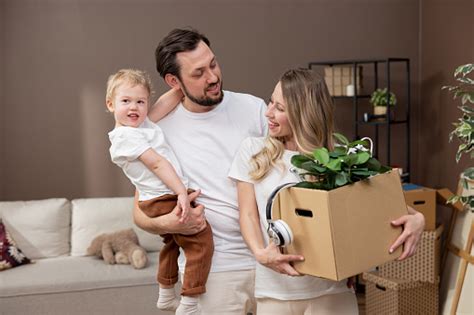 사랑에 빠진 부부는 아기와 함께 새 아파트로 이사하고 포장 된 소지품 상자를 거실로 옮기고 서로 껴안고 즐긴다 2명에 대한 스톡 사진 및 기타 이미지 Istock