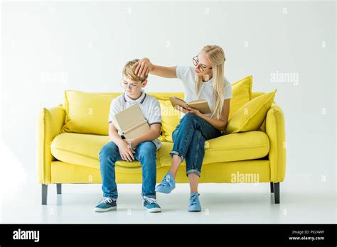 Mother Touching Son Hair While He Reading Book On Yellow Sofa Stock Photo Alamy