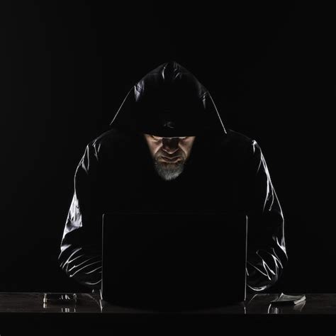 premium photo hooded masked hacker with laptop