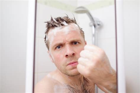 Premium Photo An Angry Man Is Showing A Fist He Takes A Shower Soaping His Head And Tries To