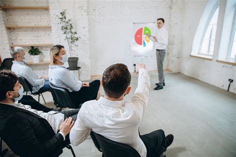 워크숍에서 홀에서 프리젠 테이션을주는 남성 스피커 청중 또는 컨퍼런스 홀 얼굴 마스크 코비드에서 인식되지 않은 참가자의 후면 보기 20 24세에 대한 스톡 사진 및 기타