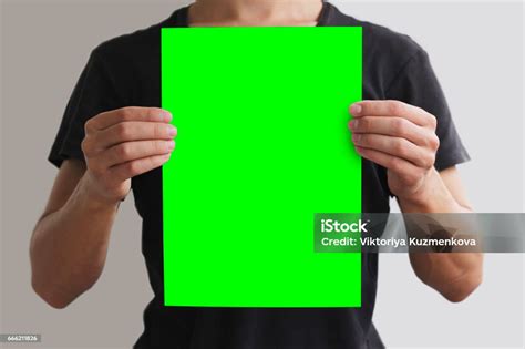 검은 색 티셔츠를 입은 남자가 빈 녹색 A4 용지를 수직으로 들고 있습니다 전단지 프리젠 테이션 팜플렛이 손을 잡습니다 남자는 명확한 오프셋 종이를 보여줍니다 시트 템플릿