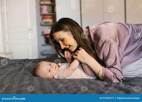 Feliz Madre Divirtiéndose Y Riendo Con Su Bebé En La Cama Imagen De