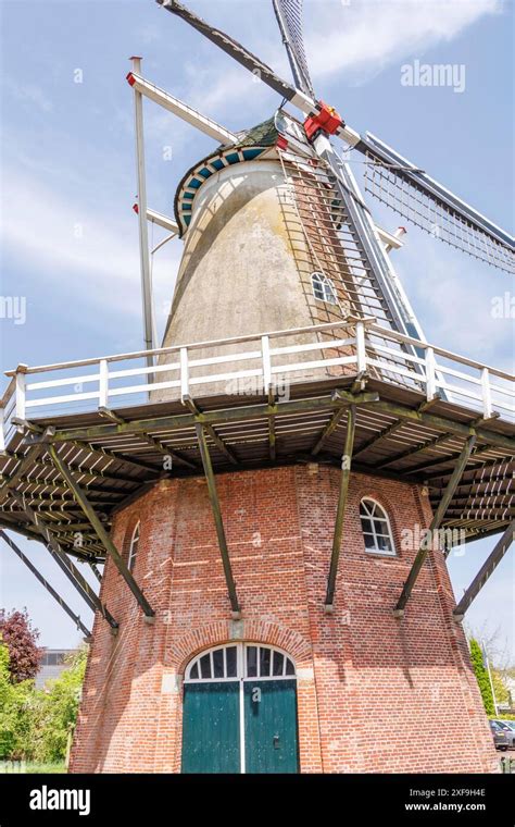 Old Brick Windmill With Traditional Wooden Structure Under A Blue Sky