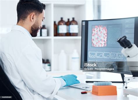 뒤에서 한 혼합 인종 과학자는 실험실에서 컴퓨터 화면에 대한 미생물학 및 유전 연구의 의료 테스트 샘플과 데이터를 분석합니다 생명 공학으로 바이러스 치료제를 개발하는 청년