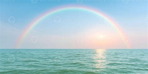 A Beautiful Rainbow Arches Over A Calm Teal Sea With A Soft Sunrise On The Horizon 73120212