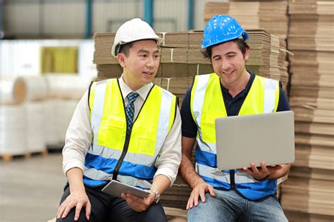 보호복을 입은 기술자 엔지니어와 사업가 그룹이 서서 산업 제조 공장에서 태블릿과 함께 토론하고 연구하고 브레인스토밍하고 계획을 세운다 2명에 대한 스톡 사진 및 기타 이미지